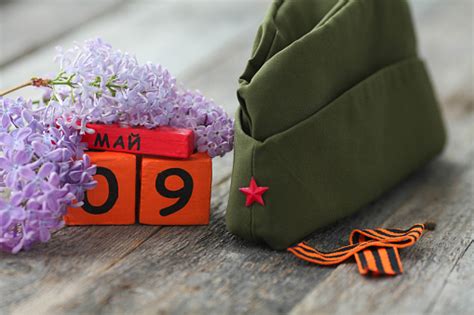 5월 9일 러시아어 텍스트가 있는 나무 달력 주둔지 모자 조지 리본 나무 배경에 라일락 꽃다발 승리의 날 1945년에 대한 스톡 사진 및 기타 이미지 Istock