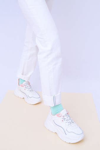 트렌디 한 캐주얼 봄 여름 의상의 세부 사항 흰색 청바지와 세련된 운동화를 입고 스튜디오에서 소녀 매일 모습 스트리트 패션 컨셉 얼굴이 없습니다 미니멀한 미학 길거리