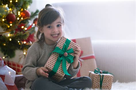 예쁜 어린 소녀는 선물 상자를 들고 집에서 그녀의 방에 그녀의 침대에 앉아있는 동안 미소 가정의 방에 대한 스톡 사진 및 기타