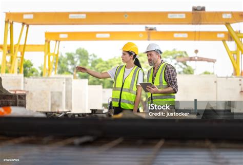 프리캐스트 공장 현장에서 프로젝트를 점검하는 엔지니어 및 여성 감독 작업자 건설 현장에서 논의하는 안전모를 쓴 엔지니어 및 건축업자 건설 산업에 대한 스톡 사진 및 기타