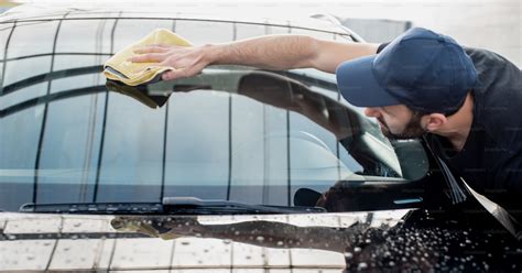 노천 세차장에서 노란색 극세사로 앞유리를 닦는 티셔츠와 모자를 쓴 전문 세탁기 사진 Unsplash의 청소 이미지