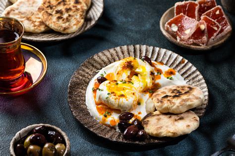 실비르 또는 터키 계란 메제 데친 달걀은 허브 그리스 요구르트 위에 얹은 다음 뜨거운 매운 파프리카 올리브 오일을 뿌립니다 라하트와 함께하는 전통 터키식 조식 건강한