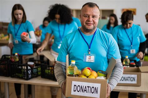 그 위에 쓰여진 기부금이 적힌 골판지 상자를 들고 음식으로 가득 찬 남자 자원봉사에 대한 스톡 사진 및 기타 이미지 자원봉사