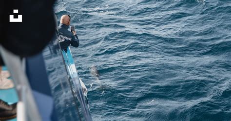 검은 재킷과 블루 데님 청바지를 입은 사람이 낮에 푸른 바다에 서 있다 사진 Unsplash의 무료 러셀 이미지