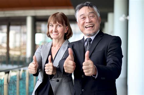 백인 사업가와 함께 양복을 입고 사무실에서 카메라를 향해 엄지손가락을 치켜세우는 행복한 미소 직장에서 성공한 노인 남성과 여성 상사 초상화 성숙한 사업가 2명에 대한 스톡