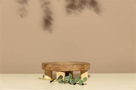 제품 프리젠 테이션을위한 빈 둥근 나무 연단과 유칼립투스는 화장품 모형을위한 베이지 색 배경에 잎 도시를 벗어난 장면에 대한