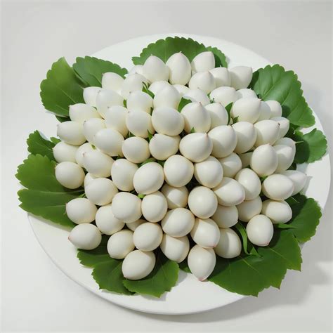 There Is A Plate Of White Eggs And Green Leaves On A White Table