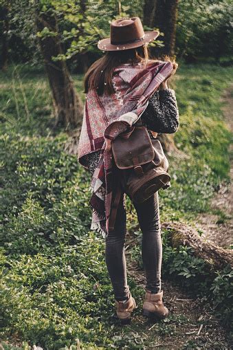 저녁 햇살에 숲에서 걷는 배낭 모자에 세련 된 Hipster 소녀 여자 여행자 다시 햇빛이 나무 들 사이 볼 텍스트를 위한 공간입니다 방 랑 벽입니다 대기 순간 가을에 대한