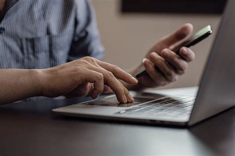 사업가가 스마트폰을 들고 노트북의 키보드를 누르고 있다 신청서 제출 노트북으로 작업하고 면접을 위해 이력서 개념을 제출하는 남자 산업 재해 보상금에 대한 스톡 사진 및 기타