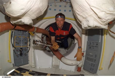 Esa Christer Fuglesang Holds A Tool As He Floats Through A Hatch On