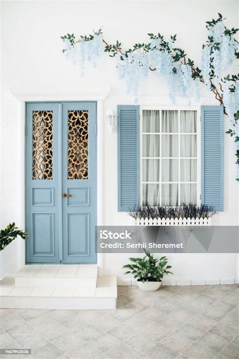 벽을 따라 엮인 꽃이 만발한 나무가 있는 지중해 스타일의 집의 흰 벽에 있는 파란색 문과 창문 산토리니의 한 집 현관 겉창에 대한 스톡 사진 및 기타 이미지 Istock