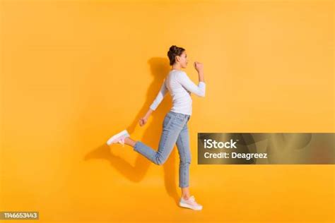 프로필 측면 보기 전체 길이 바디 크기 사진 예쁜 매력적인 젊은 여자 운동 연습 야외에서 돌진 흰색 데님 옷 빛 운동 화 화려한 배경 위에 고립 된 공원에서 갈색 머리에