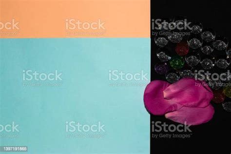 파스텔 블루 오렌지 배경 바로 옆에있는 3d 유리 구슬과 분홍색 꽃잎이있는 검은 색 배경 복사 공간으로 3차원 형태에 대한 스톡