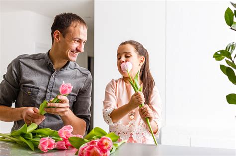 아버지는 실내 의 밝은 배경에 자신의 손에 어린 소녀를 보유하고있다 꽃과 딸과 아빠의 초상화입니다 가족 휴가의 개념입니다 아버지의 날 상반신 닫아 꽃 식물에 대한 스톡 사진