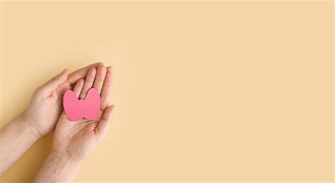 세계 갑상선의 날 여성의 손은 베이지 색 배경에 갑상선의 종이 형태를 잡고 있습니다 갑상선 문제 다낭성 질환 세계 암의 날 복사 공간을 복사합니다 기치 Charitable