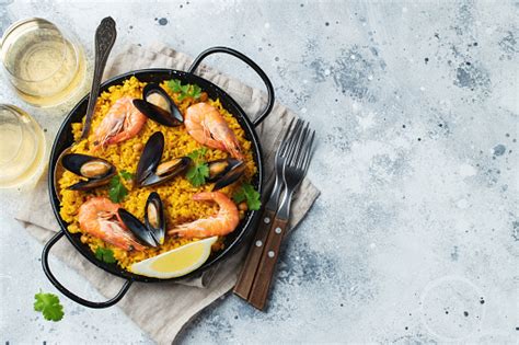 병아리콩 새우 홍합 밝은 회색 콘크리트 배경에 오징어와 팬에 전통적인 스페인 해산물 빠에야 복사 공간이 있는 상단 보기 파엘랴에