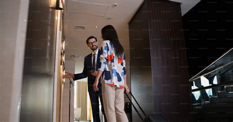 기분 좋은 미소를 지은 잘생긴 수염 난 남자가 여행 가방을 들고 아름 다운 여자를 제안하고 그 앞에 엘리베이터로 오세요 사진 Unsplash의 마루 이미지