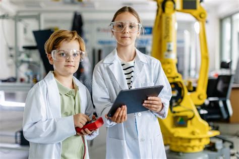 Two Classmates Standing In Robotic Laboratory Wearing Lab Coats And Safety Eyeglasses After