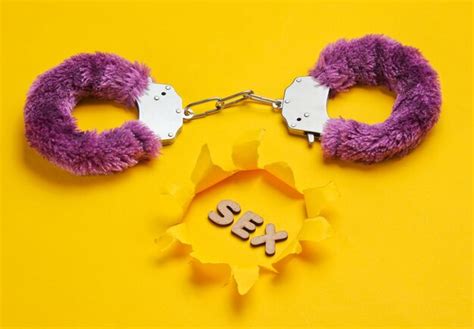 引き裂かれた穴と単語のセックスと黄色の背景のセックスゲームの手錠。性的な緊縛おもちゃ。フェチ、エロティックなコンセプト。 プレミアム写真