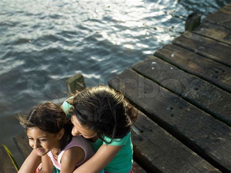 Mother And Daughter Sitting On Dock Stock Image Colourbox
