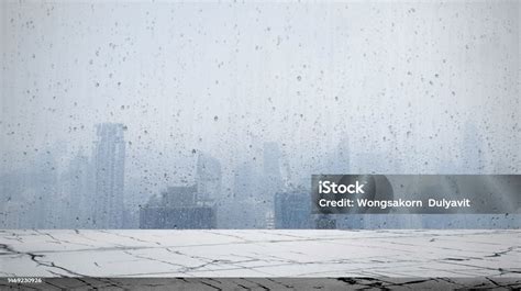 젖은 투명한 창문 유리가 있는 전경에 빈 흰색 카라라 대리석 테이블 상단 배경에 있는 고층 건물 카운터 바 전경은 디스플레이