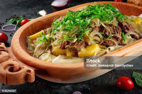 전통적인 카자흐스탄 요리 베쉬 바르 막 나무 접시에 양파와 야채를 듬뿍 넣은 양고기와 쇠고기의 향기로운 로스트 Astau 0명에