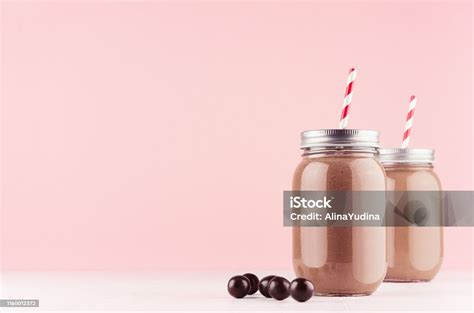 달콤한 사탕 공 복고풍 항아리에 초콜릿 밀크 쉐이크 흰색 나무 테이블에 현대 세련된 핑크 인테리어에 빨간 빨대 복사 공간
