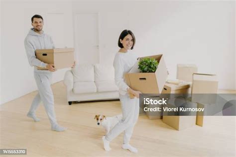 행복 한 미소 갈색 머리 여자와 그녀의 남편의 사진 개인 소지품 새 아파트에 Relocare 빈 방을 입력 새로운 생활을 시작 작은 개 근처 이동 하루를 즐길 수 있는