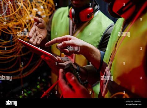 Low Angle Portrait Of Two Technicians Using Tablet While Repairing Server And Setting Up Network