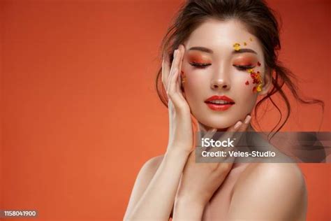 오렌지 메이크업 Anf 자연 꽃과 우아한 여자는 오렌지 배경에 그녀의 얼굴을 만지고 메이크업 화장품에 대한 스톡 사진 및 기타