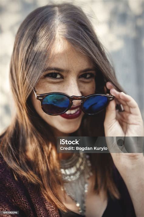 세련 된 Hipster 소녀 나무 벽 배경 밝은 거리에 웃 고 멋진 옷과 선글라스 햇빛과 그림자에서 포즈 Boho 여자의 초상화