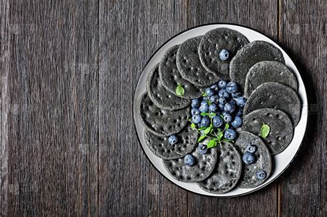 黑甜煎饼配蓝莓和薄荷放在木桌上从上面看平铺空间自由