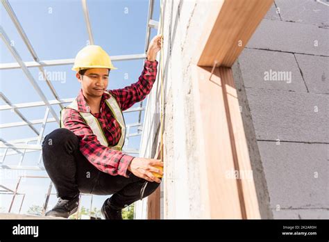 Construction Worker Or Contractor Man Using Measuring Tape Checking From Steel Roof Frame To The