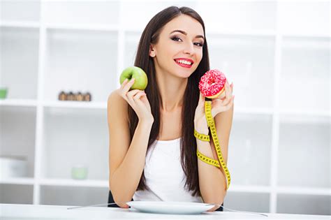 다이어트입니다 여 자가 측정 몸 무게에 무게 규모 들고 도넛 그리고 애플 과자는 건강에 해로운 정크 푸드 다이어트 건강 한 식 생활 라이프 스타일입니다 체중 감량입니다