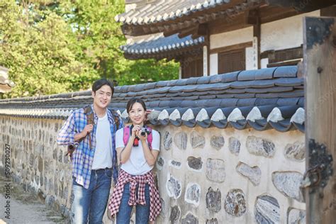 Foto De 한국의 옛날 전통 가옥 건물을 배경으로 여행 또는 가이드 하고 있는 젊은 남녀 커플 또는 친구 아시아 모델 Do Stock Adobe Stock