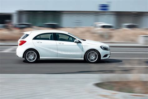 Side View Rolling Shot With White Car In Motion Mercedes A Class W176 Driving Along The Street