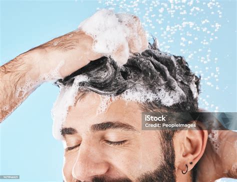 얼굴 물 튀김 파란색 배경에 스튜디오에서 샴푸를 들고 샤워하는 남자 스킨 케어 피부과 물방울 및 남성 모델 청소 목욕 또는 모발 관리 위생 및 웰빙을위한 세탁 남자에 대한