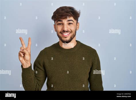 Arab Man With Beard Standing Over Blue Background Smiling With Happy
