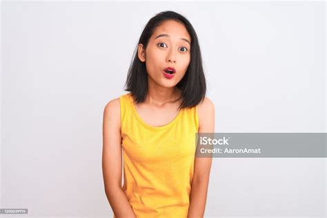 노란 캐주얼 티셔츠를 입은 젊은 중국 여성은 고립 된 흰색 배경 위에 서서 놀라움과 두려움 흥분된 얼굴로 충격을 받았습니다 T 셔츠에 대한 스톡 사진 및 기타 이미지