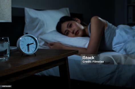 Depressed Young Asian Woman Lying Awake In Bed Struggling With Insomnia