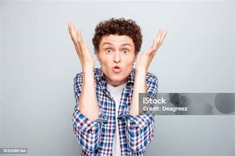 음 어떻게 예기치 않은 뉴스에 의해 놀라게 하 고 같은 시간 젊은 사람을 그의 손으로 얼굴을 찡 그리기 죠 하 고 카메라에 보이는에 실망의 빛 회색 배경에 고립 갈색 머리에