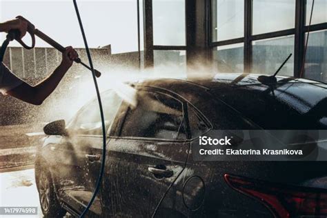 한 남자가 가압 된 물로 호스를 사용하여 셀프 서비스 세차장에서 차를 씻습니다 세차장에 대한 스톡 사진 및 기타 이미지