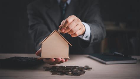 저축과 투자를 상징하는 목조 주택 모델에 동전을 놓는 손 재무 계획 부동산 모기지 은행 업무에 이상적입니다 경제 성장과 안전한 투자의 개념 가격에 대한 스톡 사진 및 기타