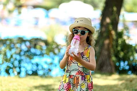 화창한 더운 날에 물을 마시는 선글라스를 쓴 화려한 드레스와 모자를 쓴 귀여운 유아 소녀 여름 방학에 즐거운 시간을 보내는 행복한 아이 열 개념에 대한 스톡 사진 및 기타