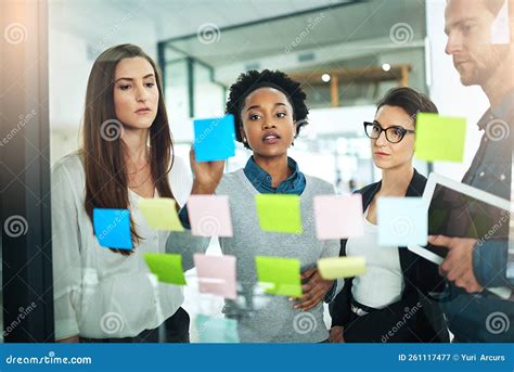 Theyre Focused On Their Plan Coworkers Using Sticky Notes On A Glass Wall During A Meeting