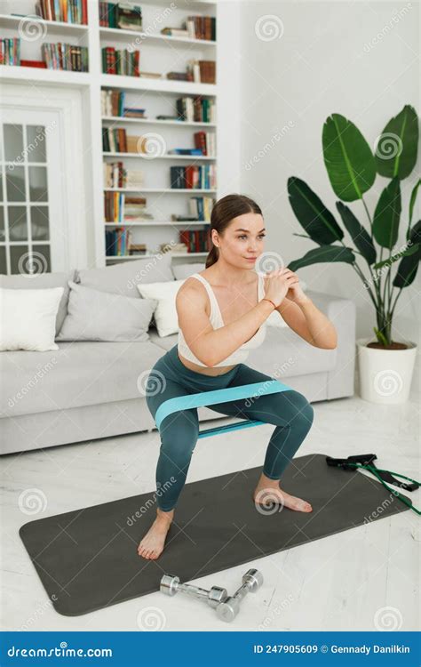 Athletic Young Woman Doing Morning Exercises Squatting Alone In The Living Room Serious Girl In