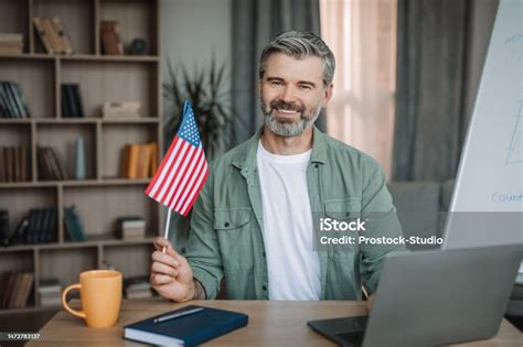 수염 선생님을 가진 쾌활한 은퇴한 유럽 남자는 노트북에 미국 국기 촬영 비디오 수업을 개최 40 44세에 대한 스톡 사진 및 기타 이미지 40 44세 Brand