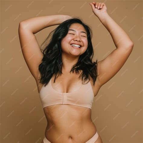 Smiling Asian Woman Embracing Her Body While Standing In A Studio In
