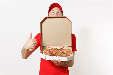 배달 빨간 유니폼을 입고 흰색 배경에 고립 된 사람을 웃 고 모자 티셔츠 택배 또는 골 판지 Flatbox에서 이탈리아 피자를 들고 딜러로 일하고 있는 남자 Pizzaman