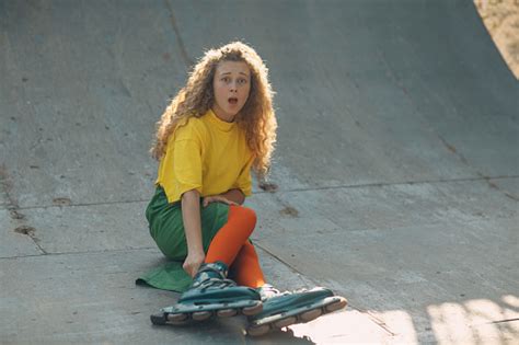 곱슬 헤어 스타일 롤러 스케이트와 녹색과 노란색 옷과 오렌지 스타킹에 젊은 여자 소녀는 스케이트 공원에서 떨어졌다 건강한 생활방식에 대한 스톡 사진 및 기타 이미지 Istock